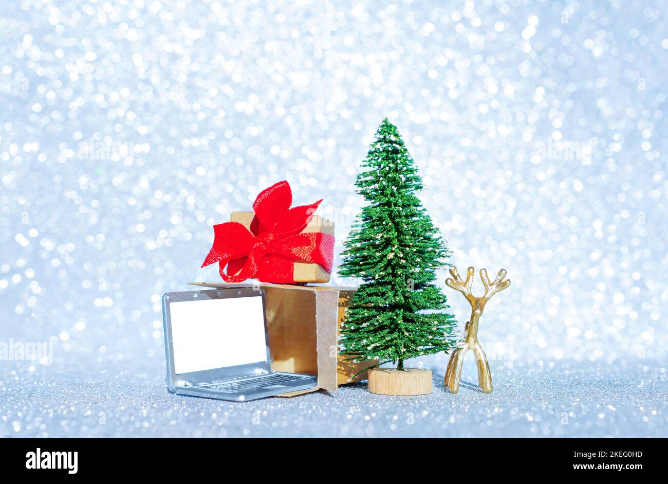 Miniature notebook computer by a toy christmas tree with glittering ...