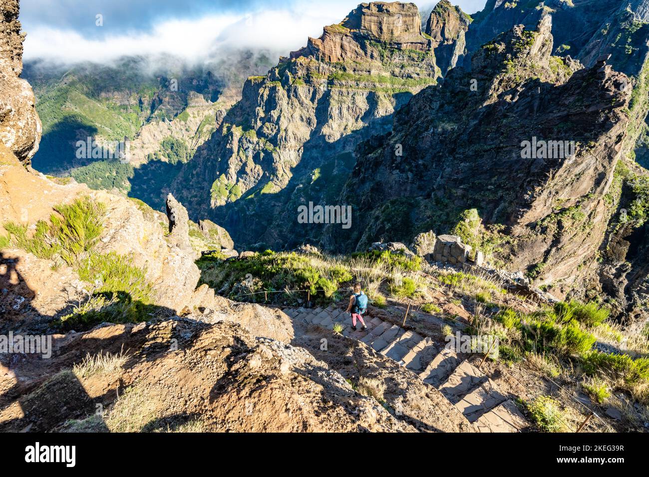 Description: Woman with backpack hiking down steep stairs along very ...