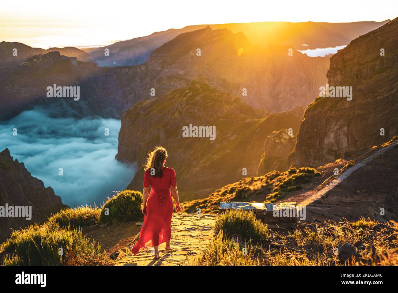 Description: Beautiful woman in red dress walking barefoot on a very ...