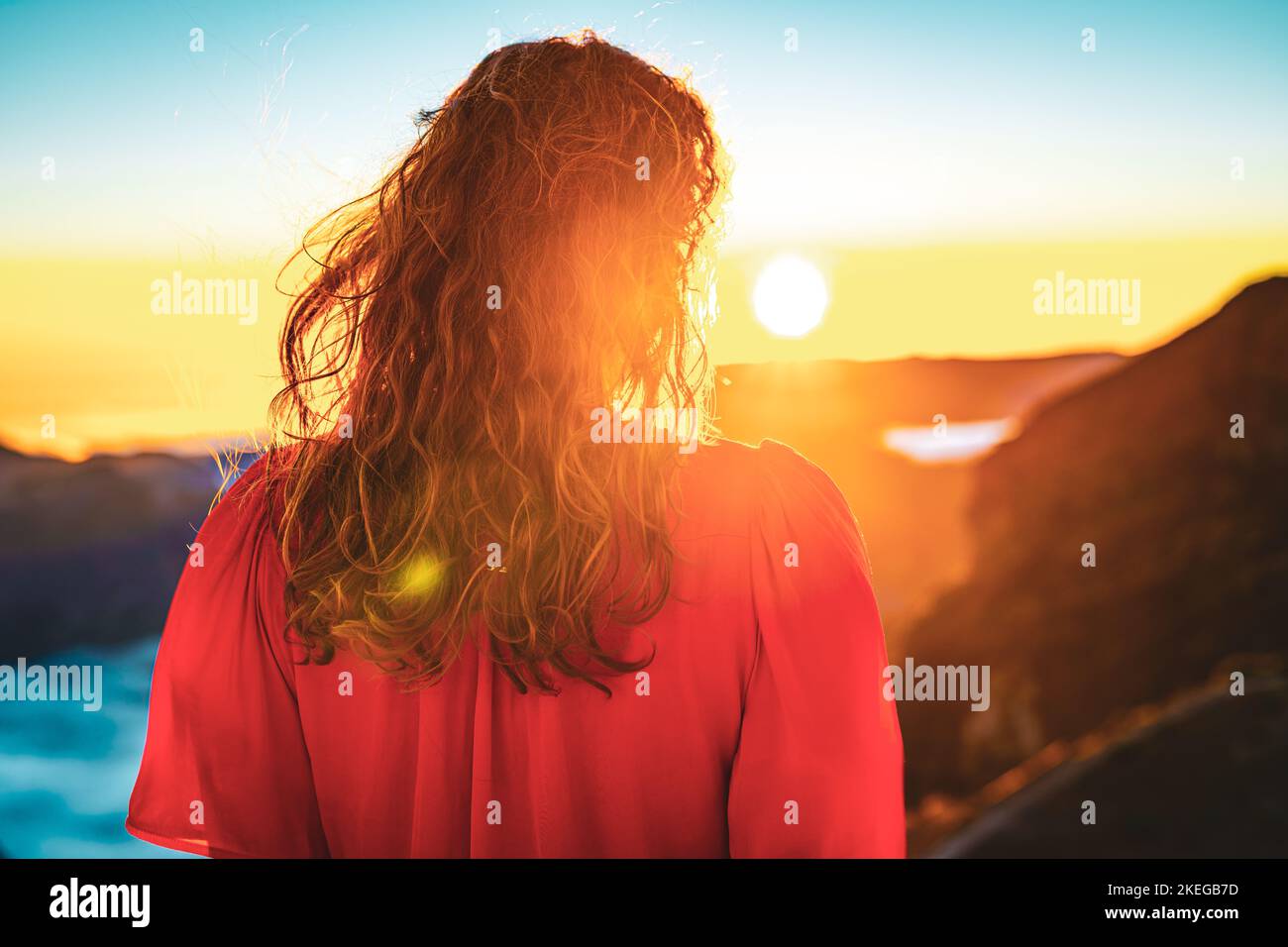 Description: Beautiful woman in red dress enjoying sunny evening ...