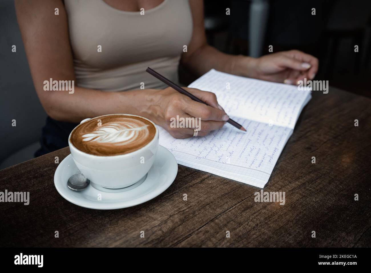 Unrecognizable woman sits at table in cafe with cup of coffee and ...
