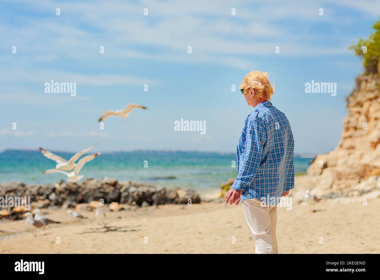 Elderly woman standing on the beach and looking into the distance Stock ...