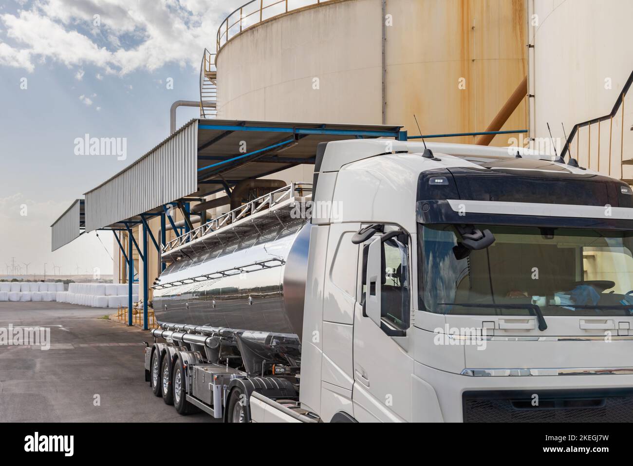 Tanker truck loading liquid next to some large tanks Stock Photo - Alamy