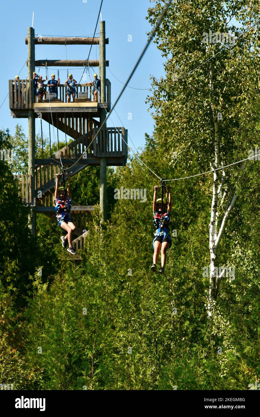 Children high adventure on zipline course through forest canopy with ...