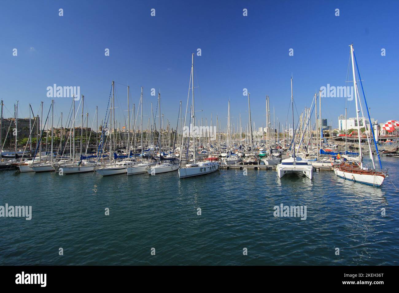 A scenic view of the Barcelona harbor with sailboats on a clear sunny ...
