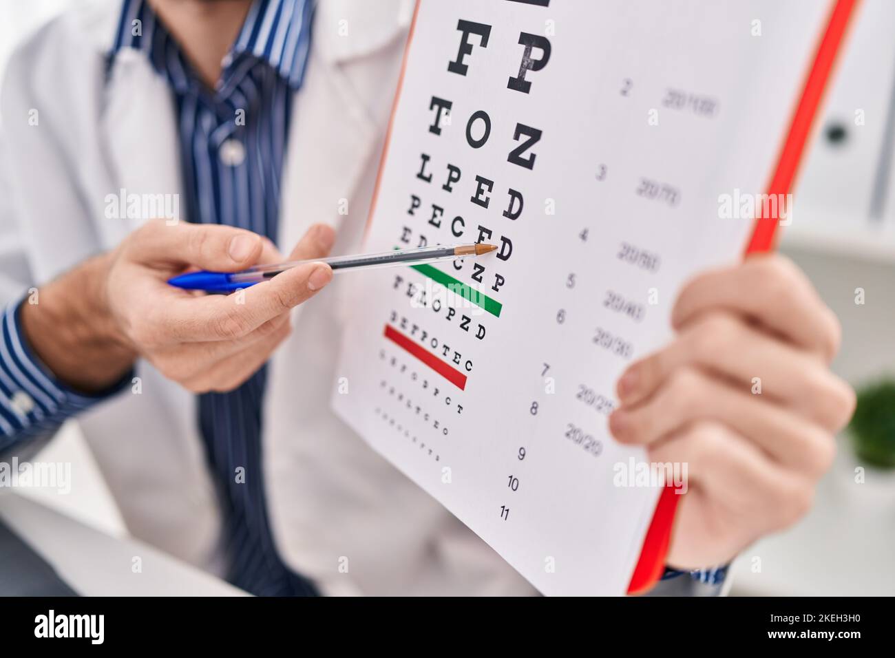 Young man optician holding snellen test at clinic Stock Photo - Alamy