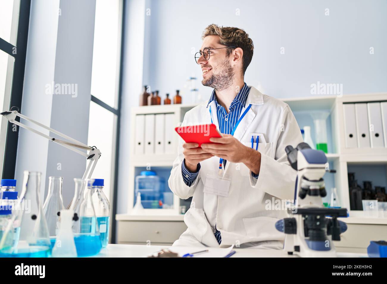 Young man scientist smiling confident using touchpad at laboratory Stock Photo - Alamy