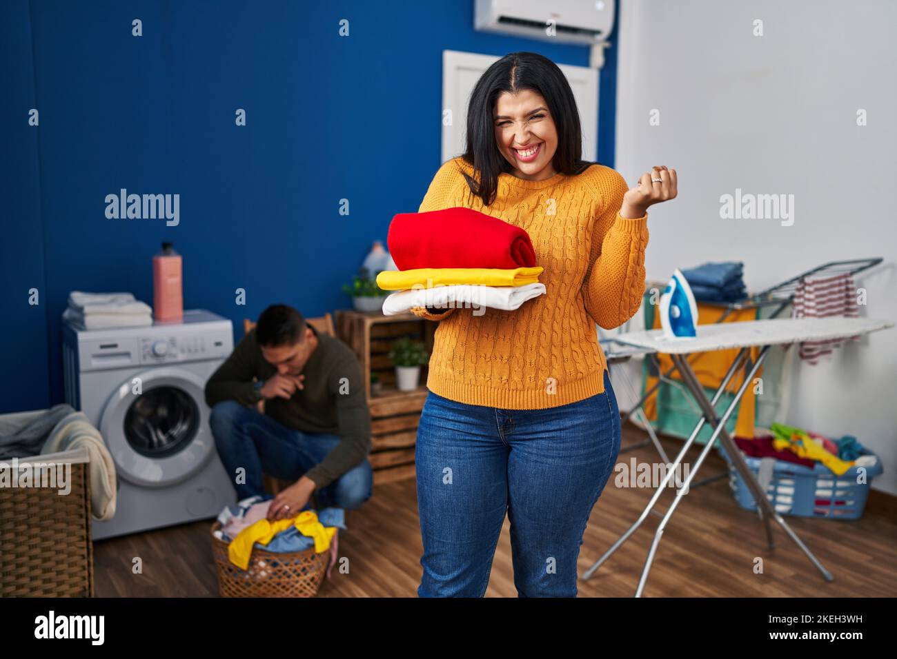 Young couple doing laundry at home screaming proud, celebrating victory ...