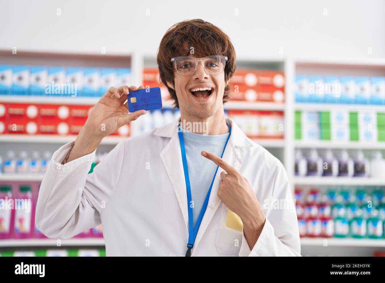Hispanic young man working at pharmacy drugstore holding credit card ...