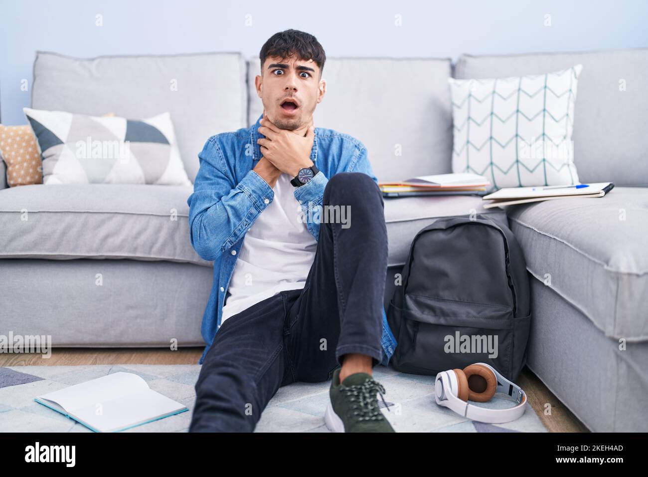 Young hispanic man sitting on the floor studying for university ...