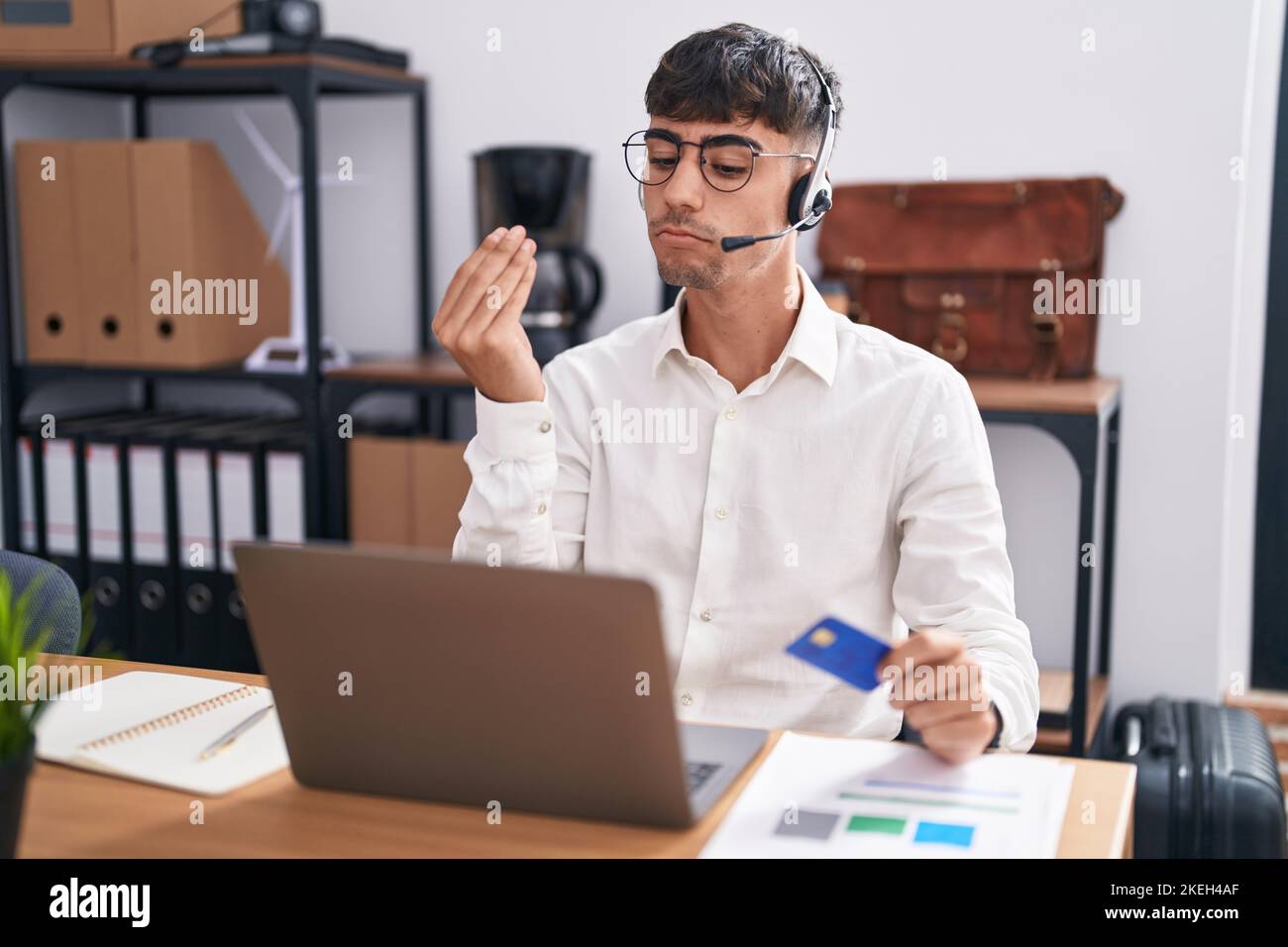 Young hispanic man working using computer laptop holding credit card ...