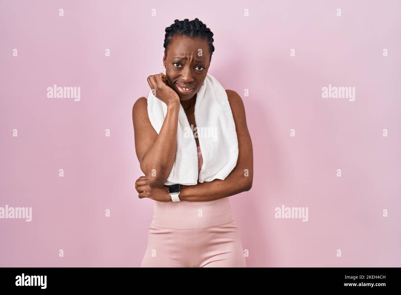 Beautiful black woman wearing sportswear and towel over pink background ...