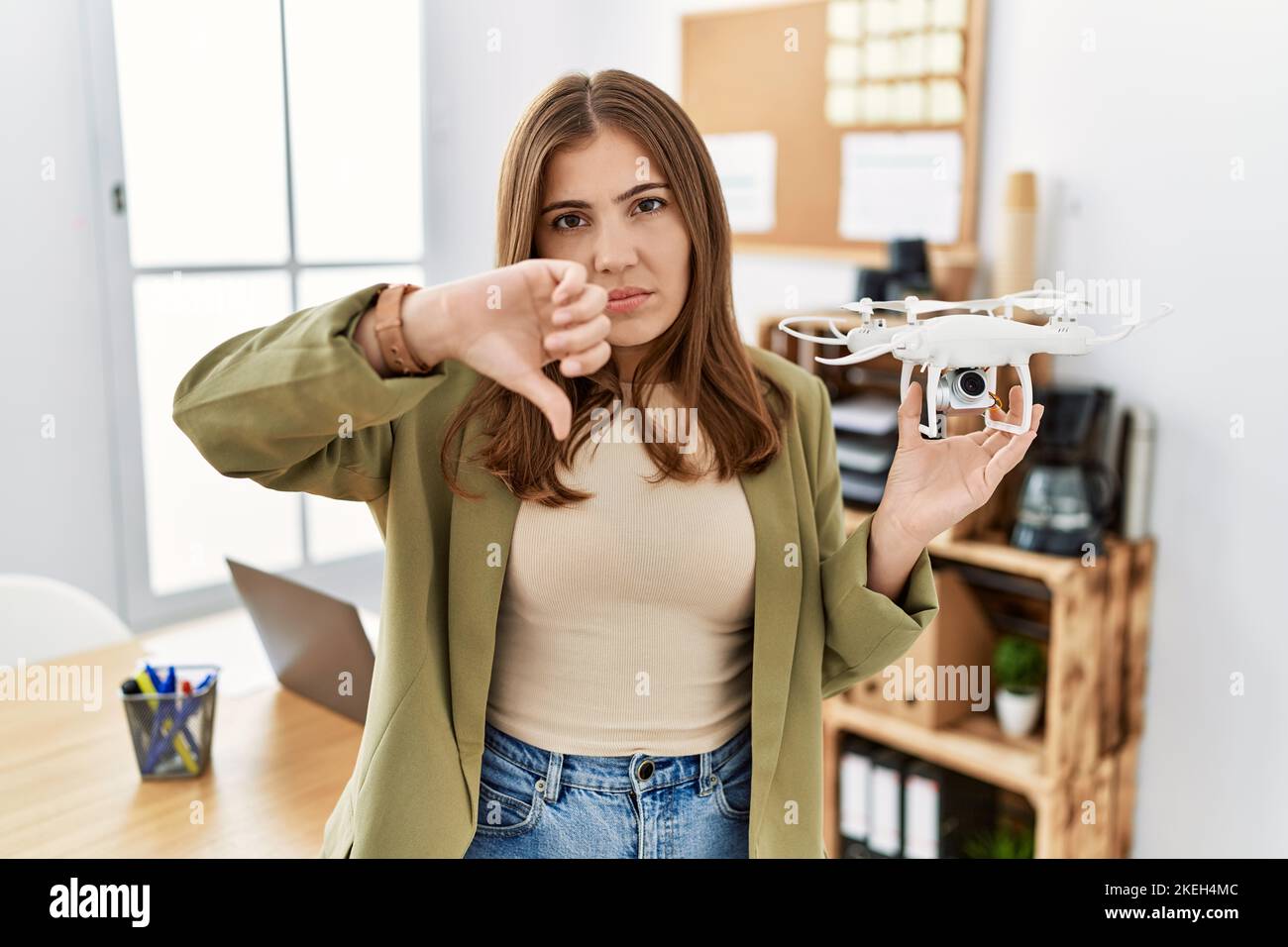 Young brunette woman holding drone at architect office with angry face ...