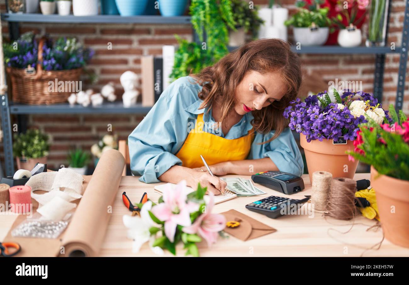 Young beautiful hispanic woman florist counting dollars at florist ...
