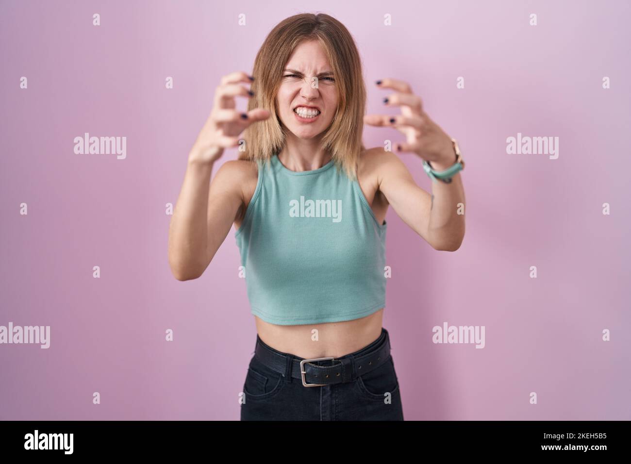 Blonde caucasian woman standing over pink background shouting ...