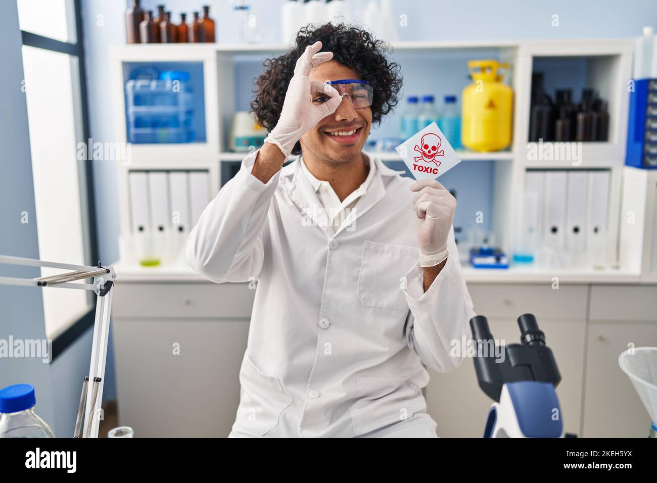 Hispanic man with curly hair working at scientist laboratory holding ...