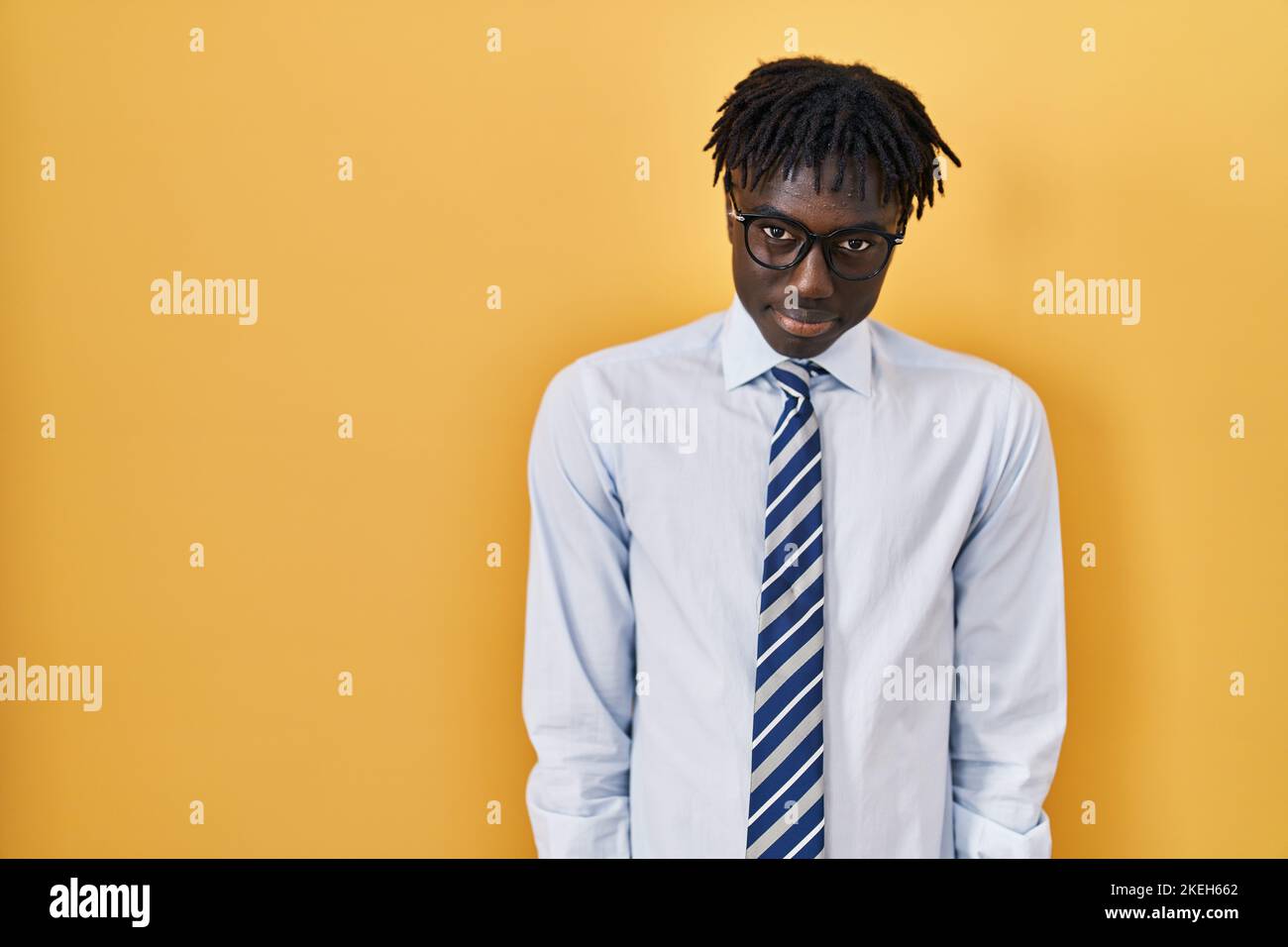 African man with dreadlocks standing over yellow background depressed ...