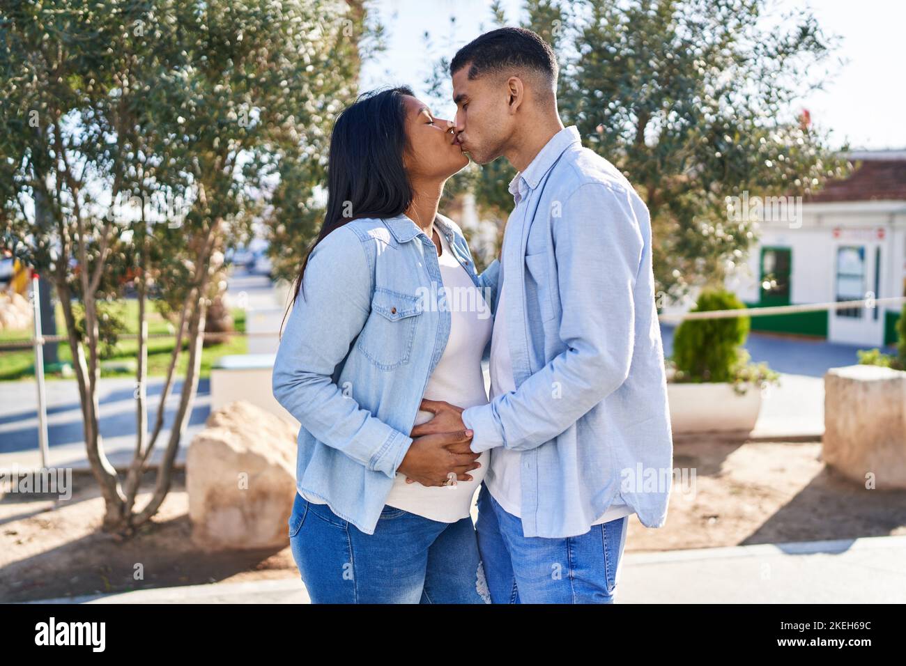 Young latin couple expecting baby hugging each other and kissing at park Stock Photo - Alamy
