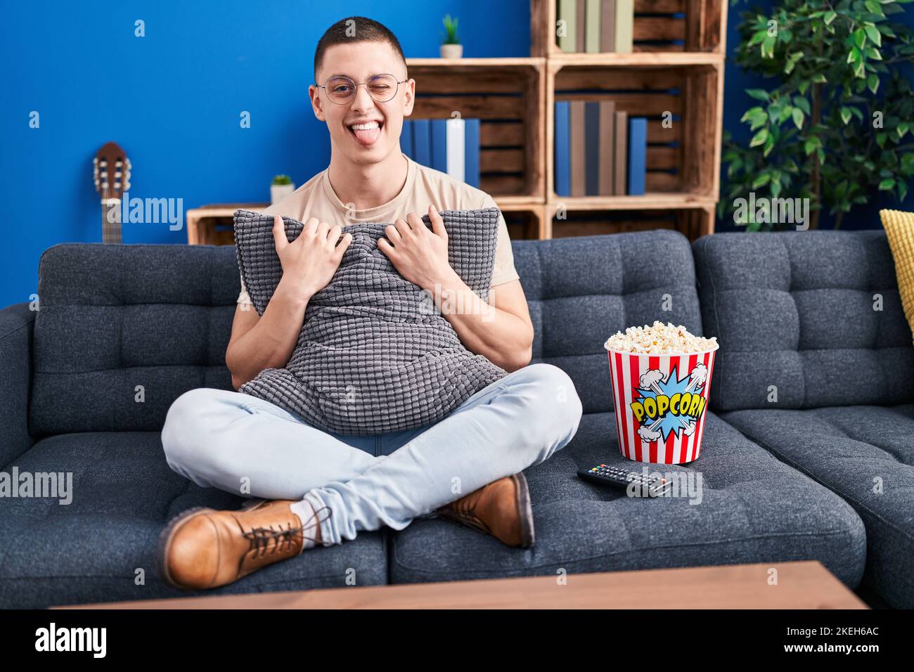 Young man eating popcorn sticking tongue out happy with funny ...