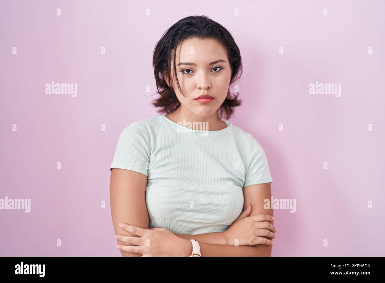 Hispanic young woman standing over pink background skeptic and nervous ...