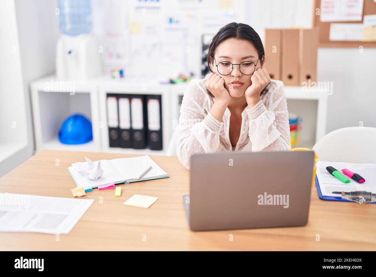 Young hispanic woman business worker using laptop with sad expression ...