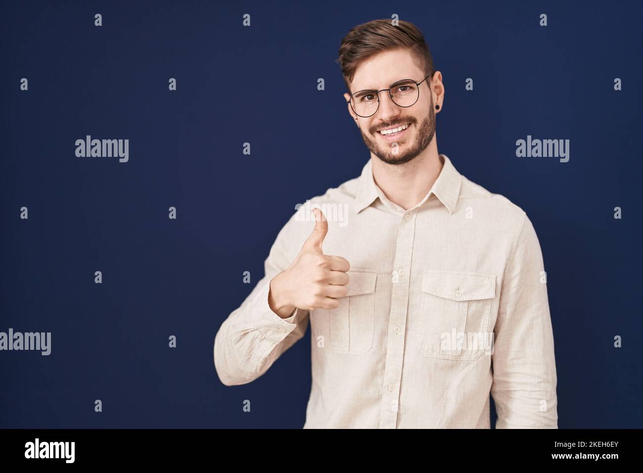 Hispanic man with beard standing over blue background doing happy ...