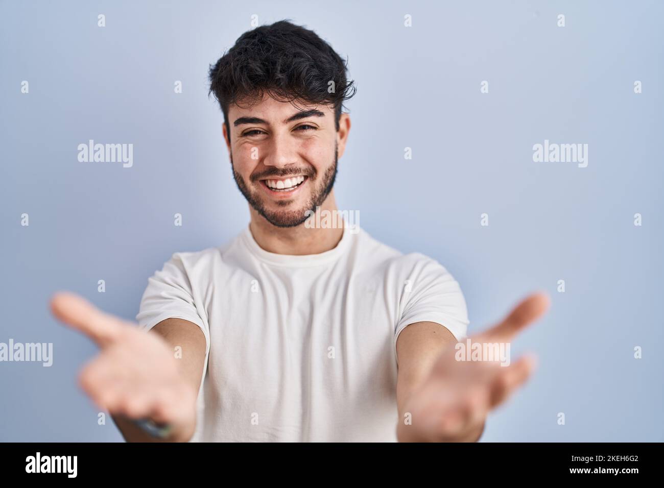 Hispanic man with beard standing over white background smiling cheerful ...