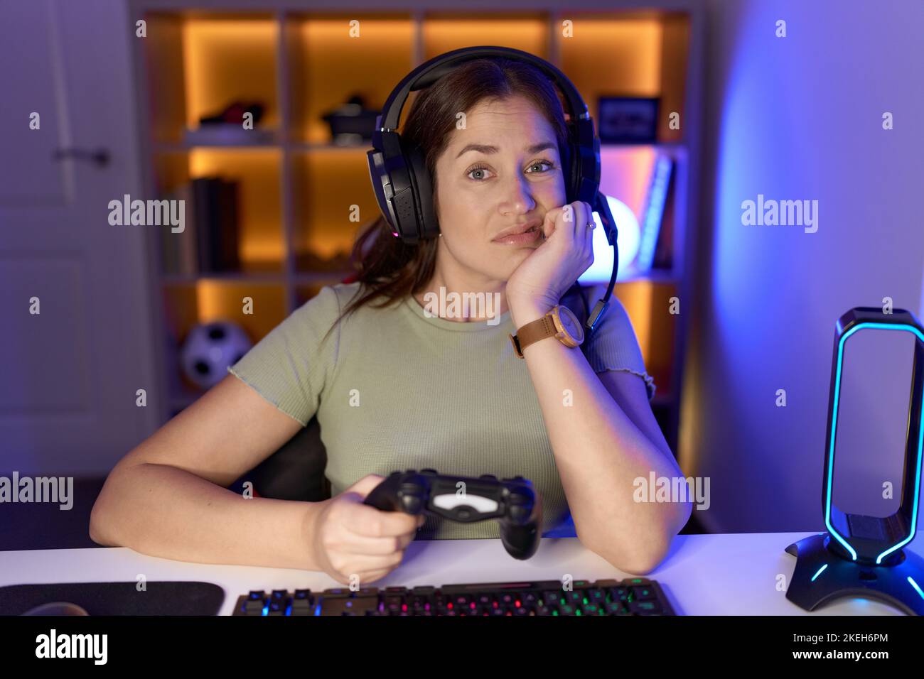Beautiful brunette woman playing video games wearing headphones looking ...