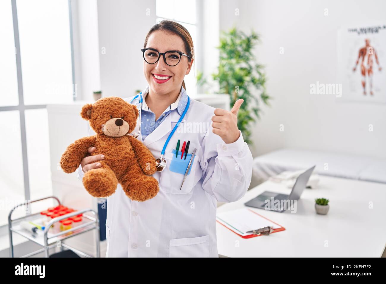 Young hispanic pediatrician woman holding teddy bear at the clinic ...