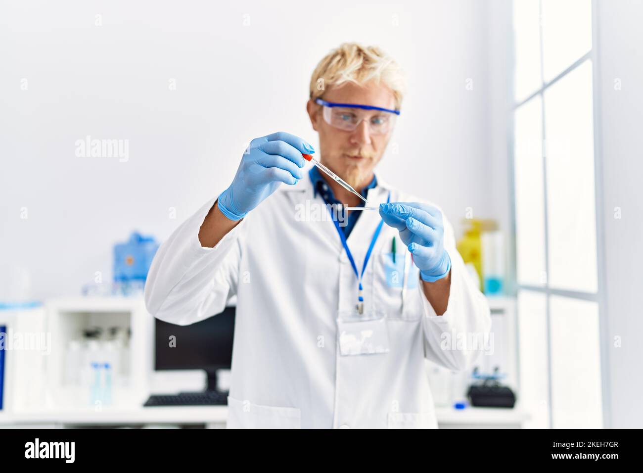 Young caucasian man wearing scientist uniform using pipette at ...