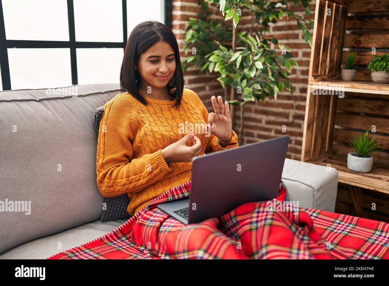 Young latin woman having video call using deaf sign language at home ...