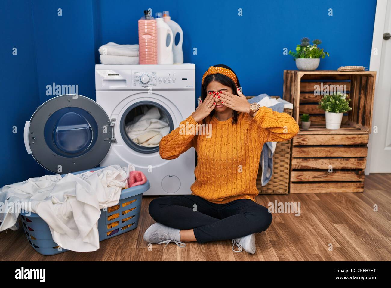 Young hispanic woman doing laundry rubbing eyes for fatigue and ...