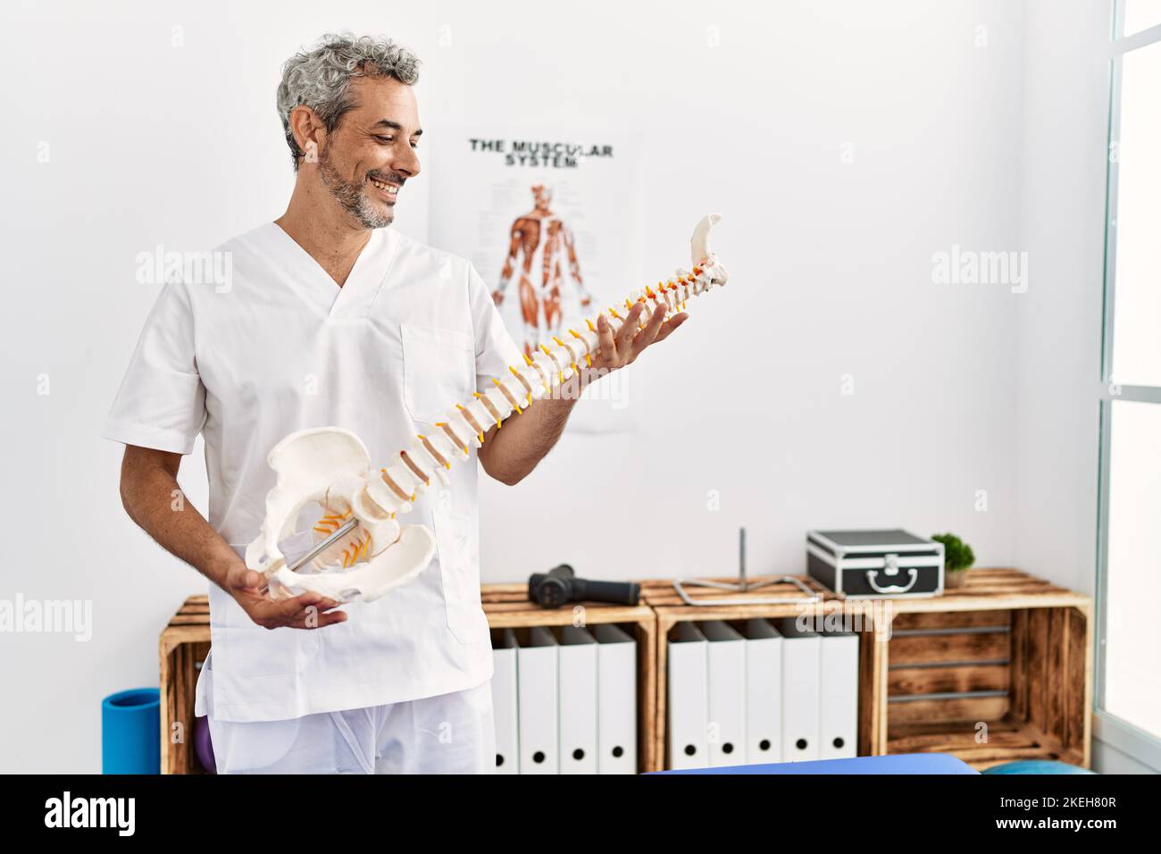 Middle age grey-haired man physiotherapist smiling confident holding ...