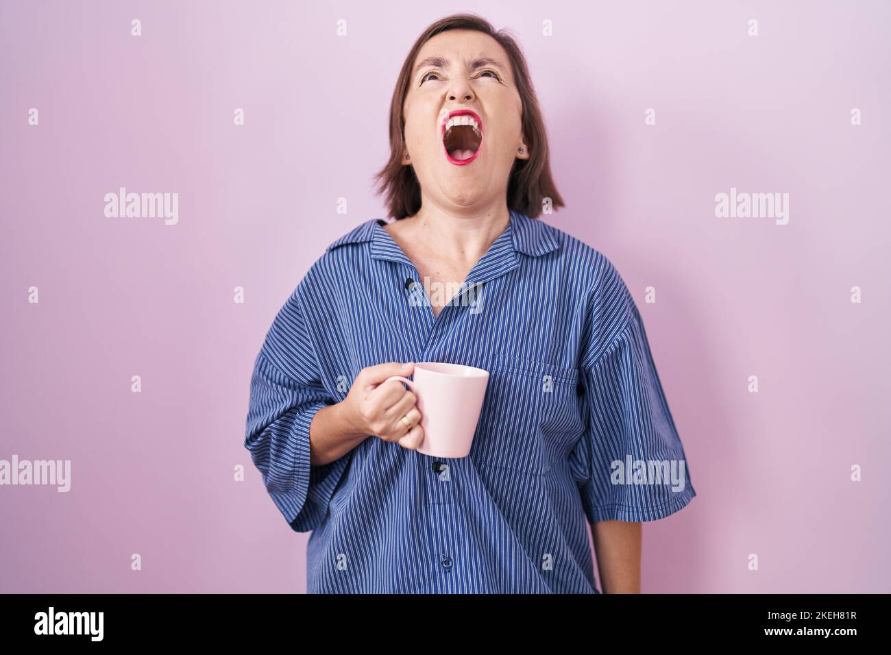 Middle age hispanic woman drinking a cup coffee angry and mad screaming ...
