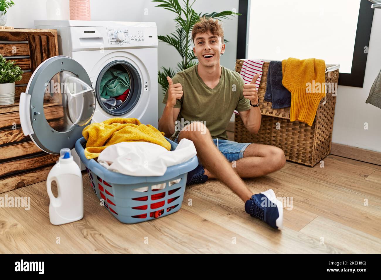 Young caucasian man putting dirty laundry into washing machine success ...