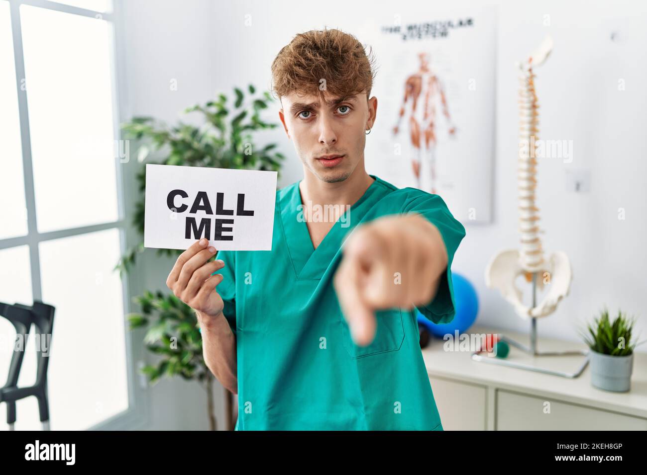 Young caucasian physio man holding call me banner at the clinic ...