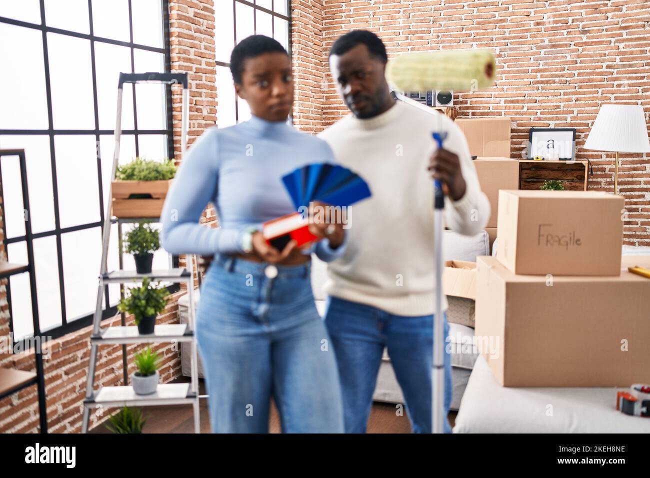 Young african american couple moving to a new home choosing walls color ...