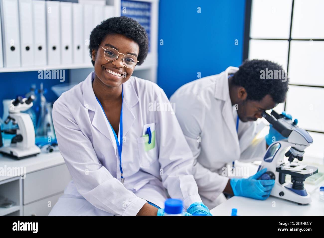 African american man and woman scientists using microscope at laboratory Stock Photo - Alamy