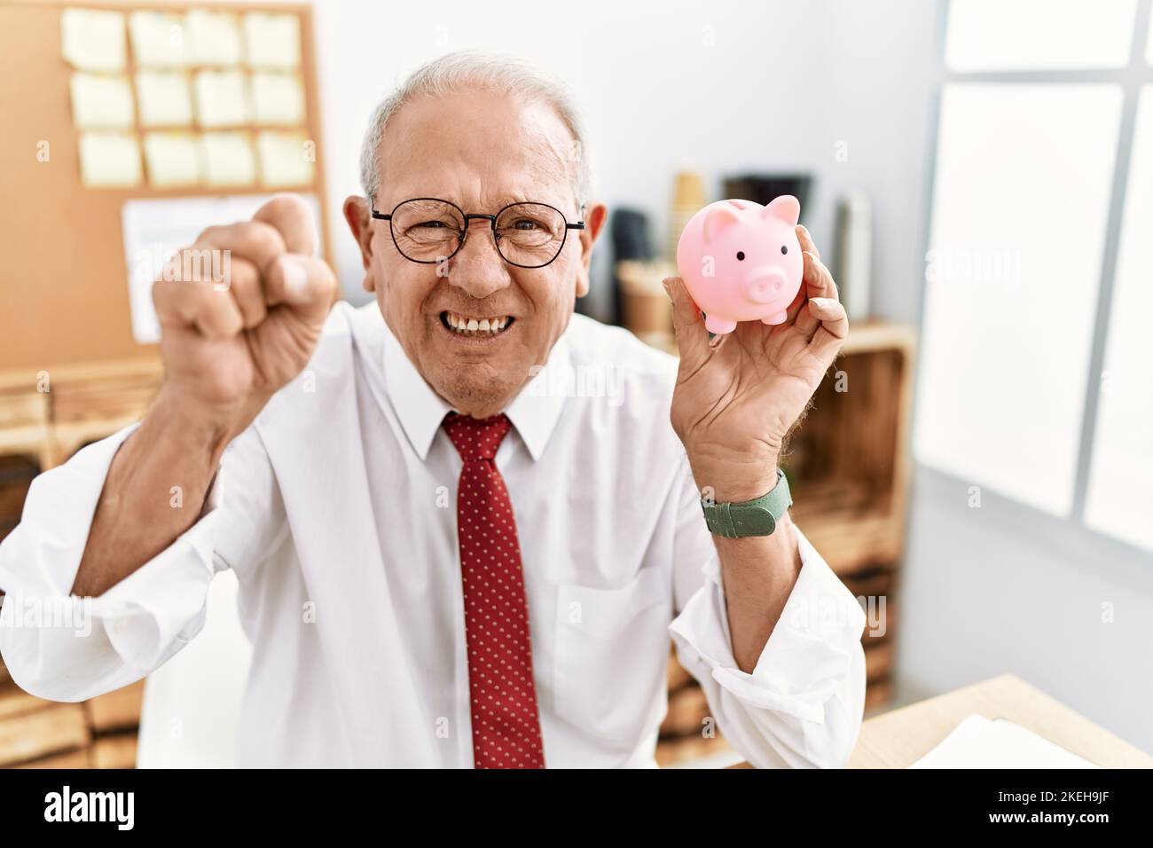 Senior business man holding piggy bank annoyed and frustrated shouting ...