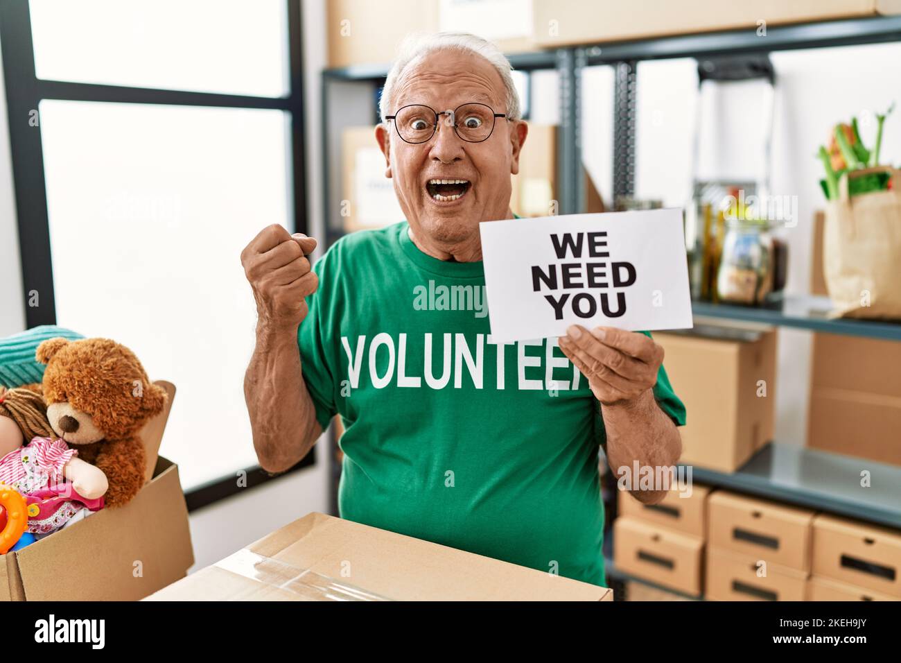 Senior volunteer man holding we need you banner screaming proud ...
