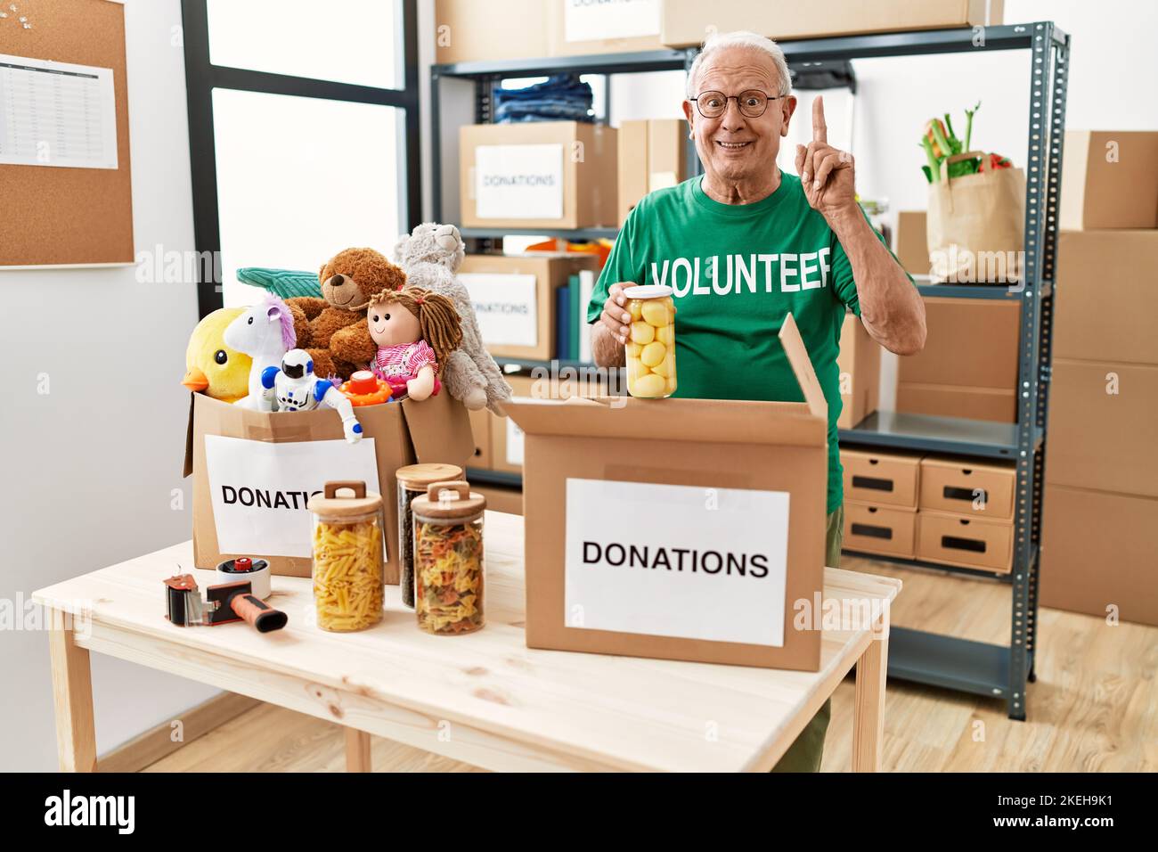 Senior man volunteer holding donations box putting food into a box ...