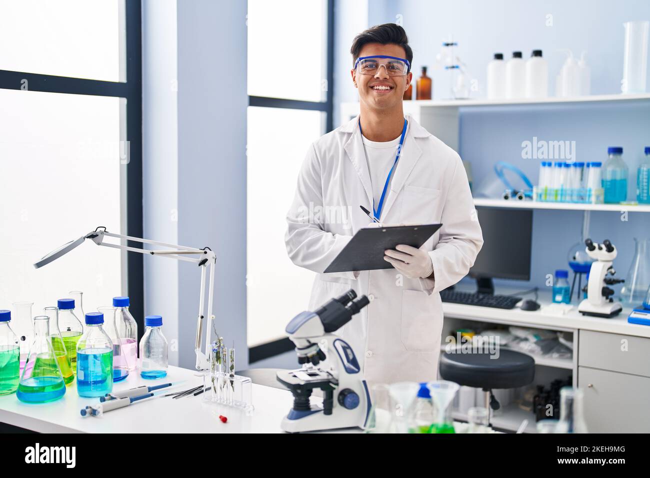 Young hispanic man scientist writing report working at laboratory Stock ...