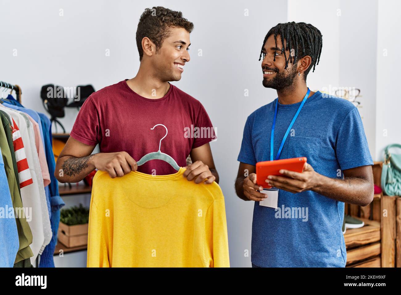 Two men asking shopkeeper for clothes size using touchpad at clothing ...