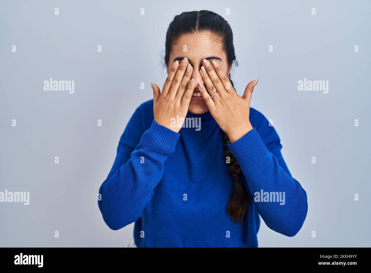 Young hispanic woman standing over isolated background rubbing eyes for ...