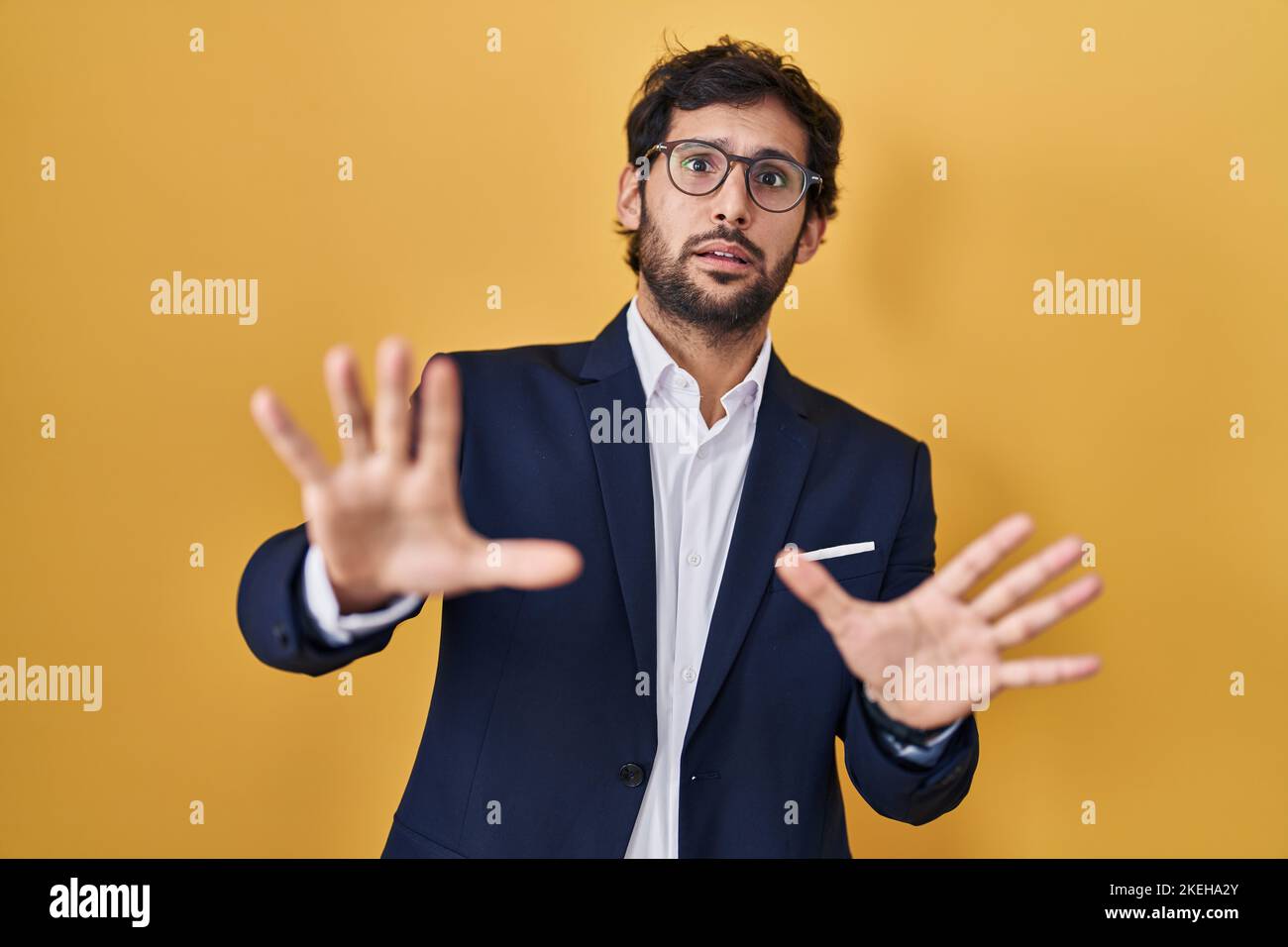 Handsome latin man standing over yellow background afraid and terrified ...