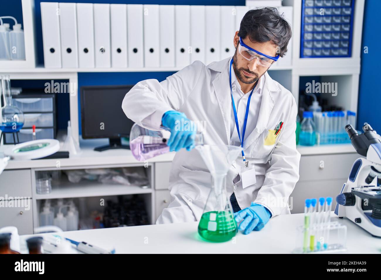 Young hispanic man scientist measuring liquid at laboratory Stock Photo ...