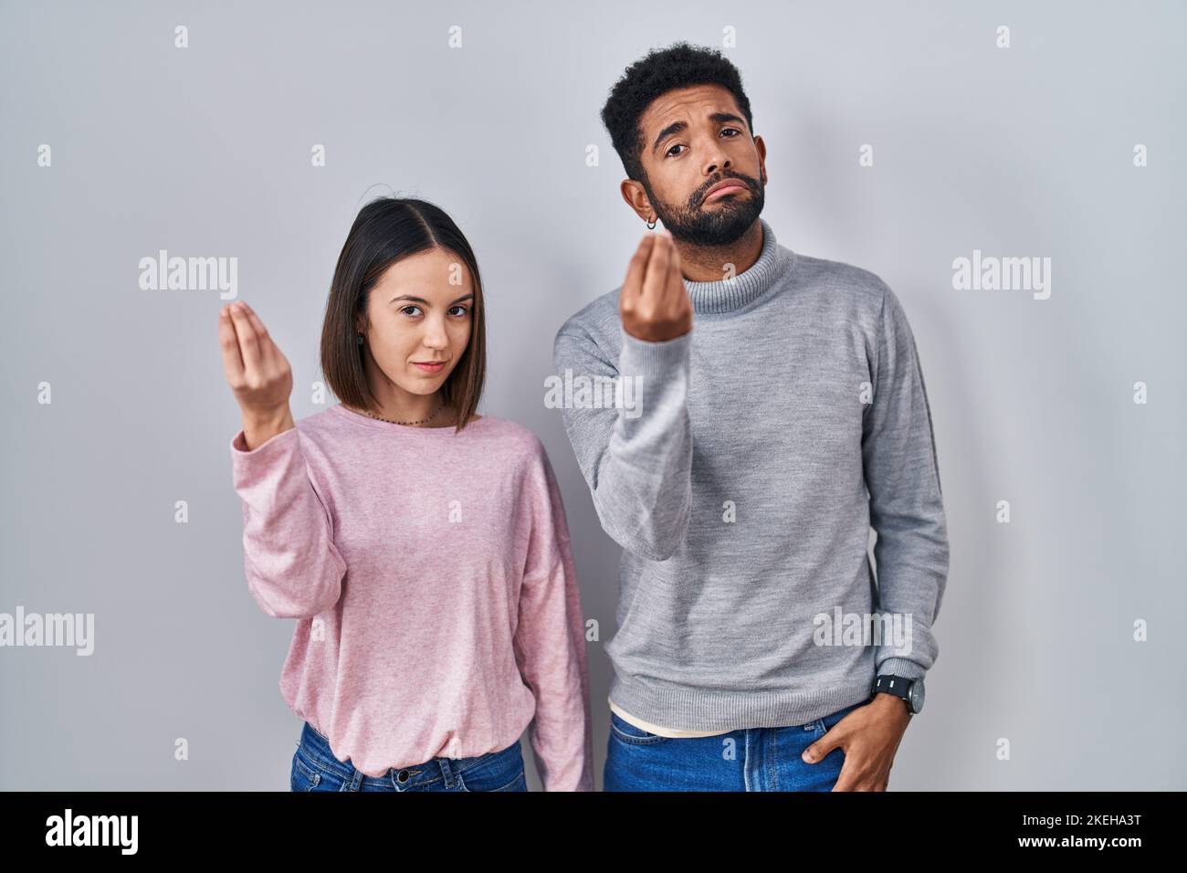 Young hispanic couple standing together doing italian gesture with hand ...