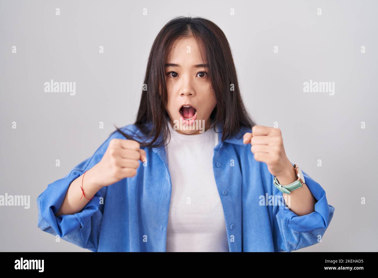 Young chinese woman standing over white background angry and mad ...
