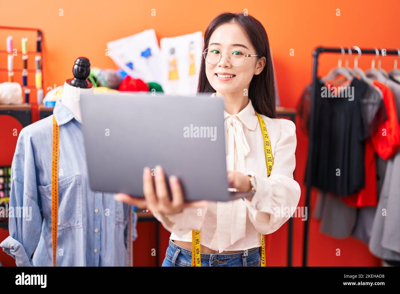 Young chinese woman tailor smiling confident using laptop at atelier ...