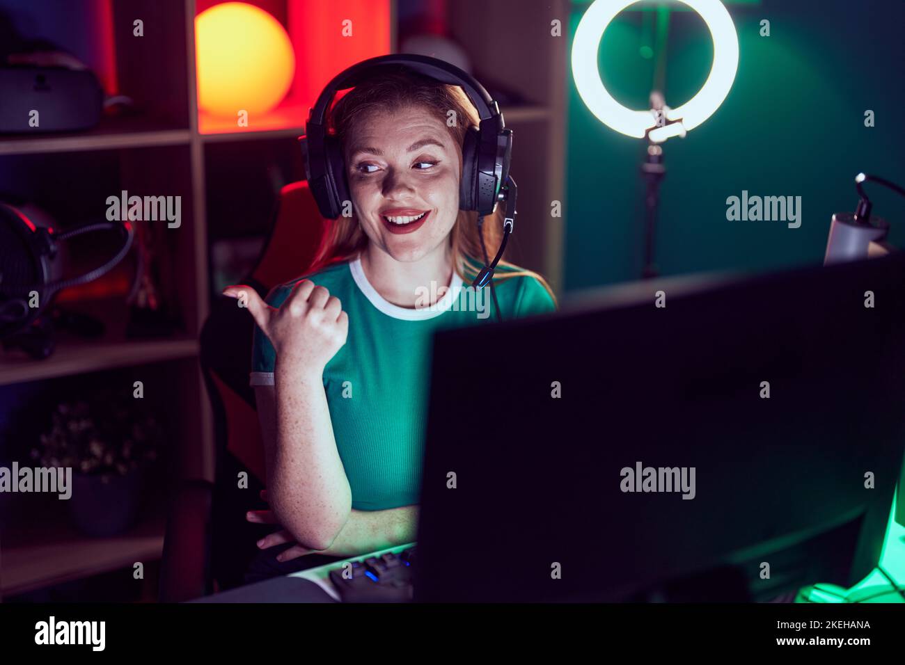 Redhead woman playing video games smiling with happy face looking and ...